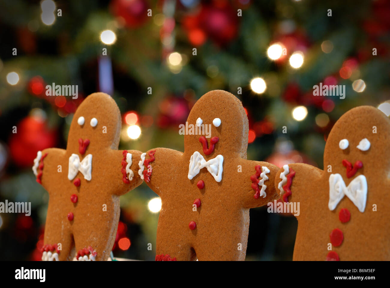 Three gingerbread men in a line in front of Christmas tree lights Stock ...