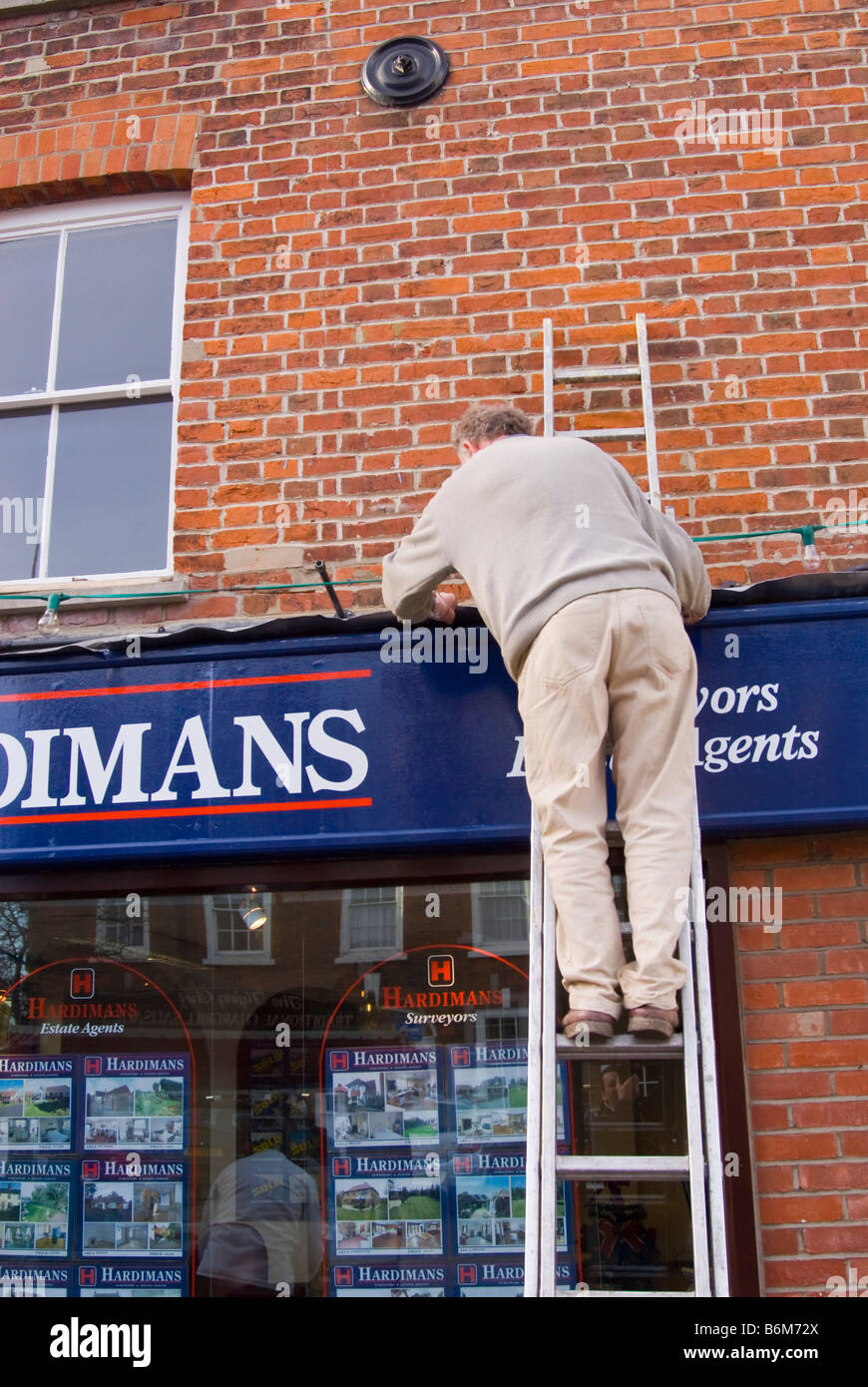 Man repairing lead flashing over a shop store sign working from a ...