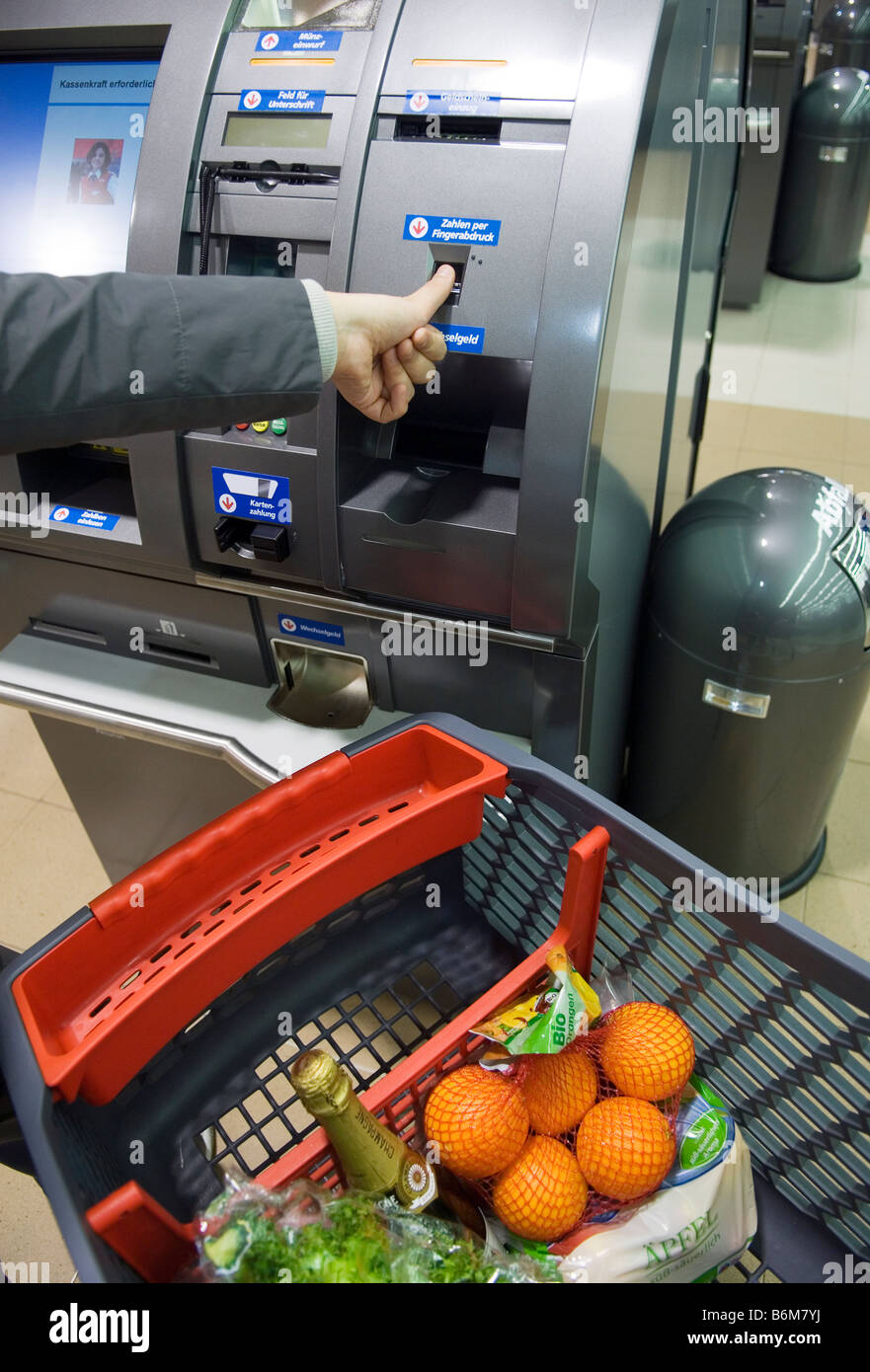 young woman uses her fingerprint to pay at the automatic cashier in the ...