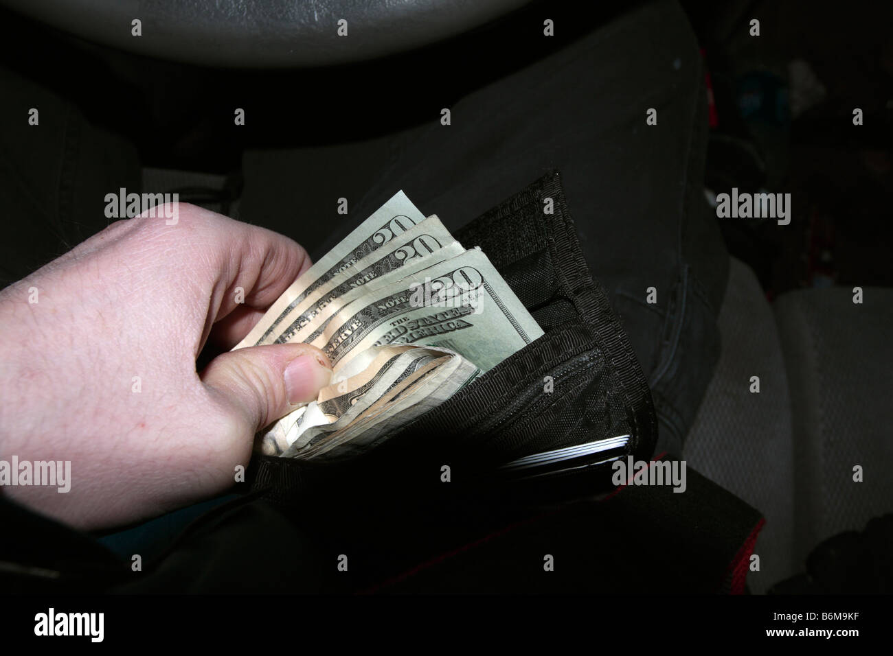 Male caucasian hand fanning small amount of money inside black nylon ...