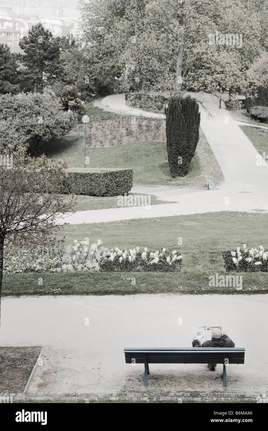 Man reading paper on a park bench in Paris Stock Photo - Alamy
