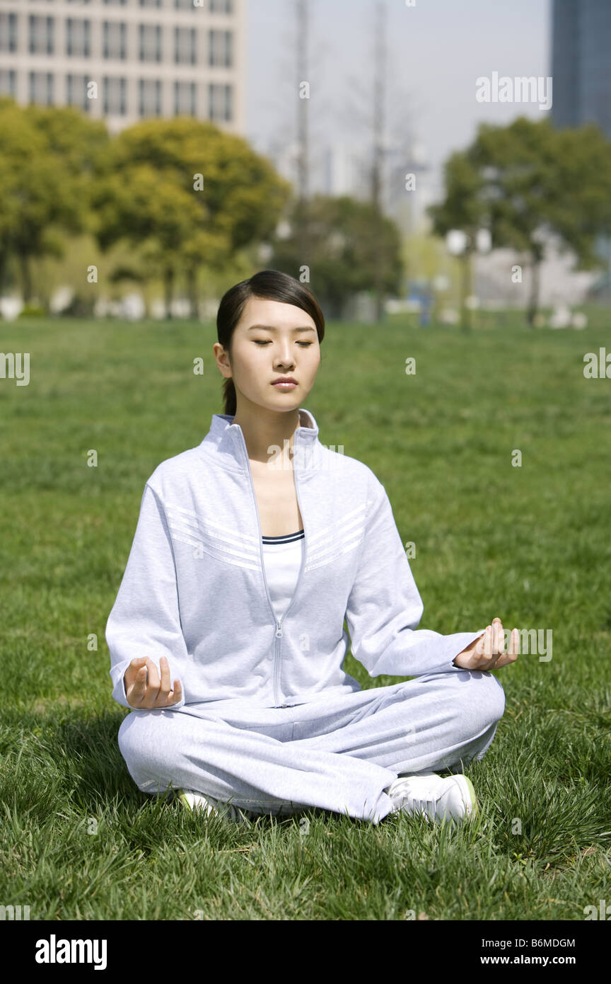 Young woman in lotus position on lawn Stock Photo - Alamy