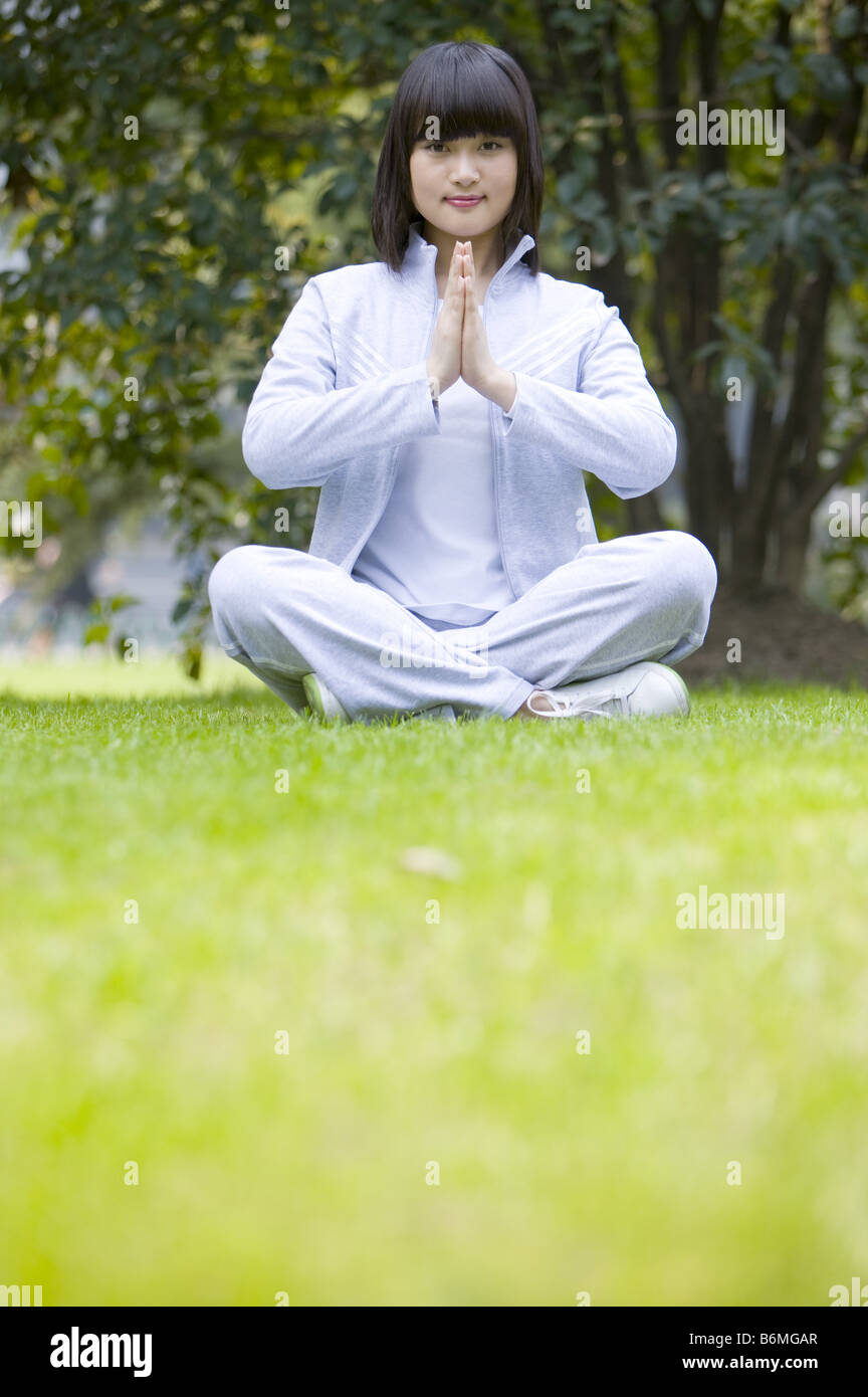 Young woman sitting on lawn in prayer position Stock Photo - Alamy
