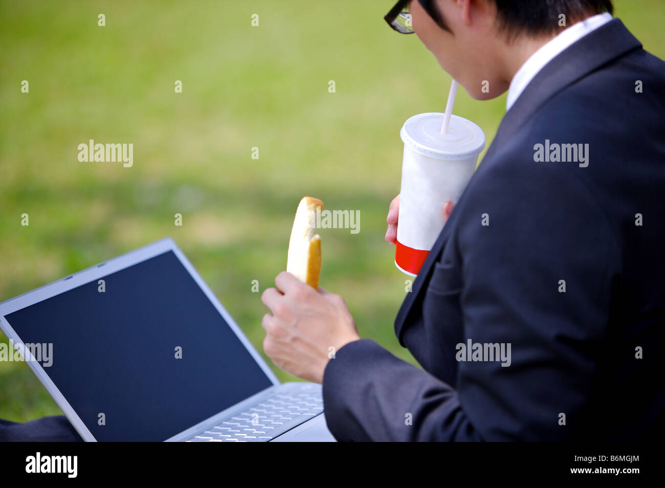 Young woman eating food with laptop Stock Photo - Alamy
