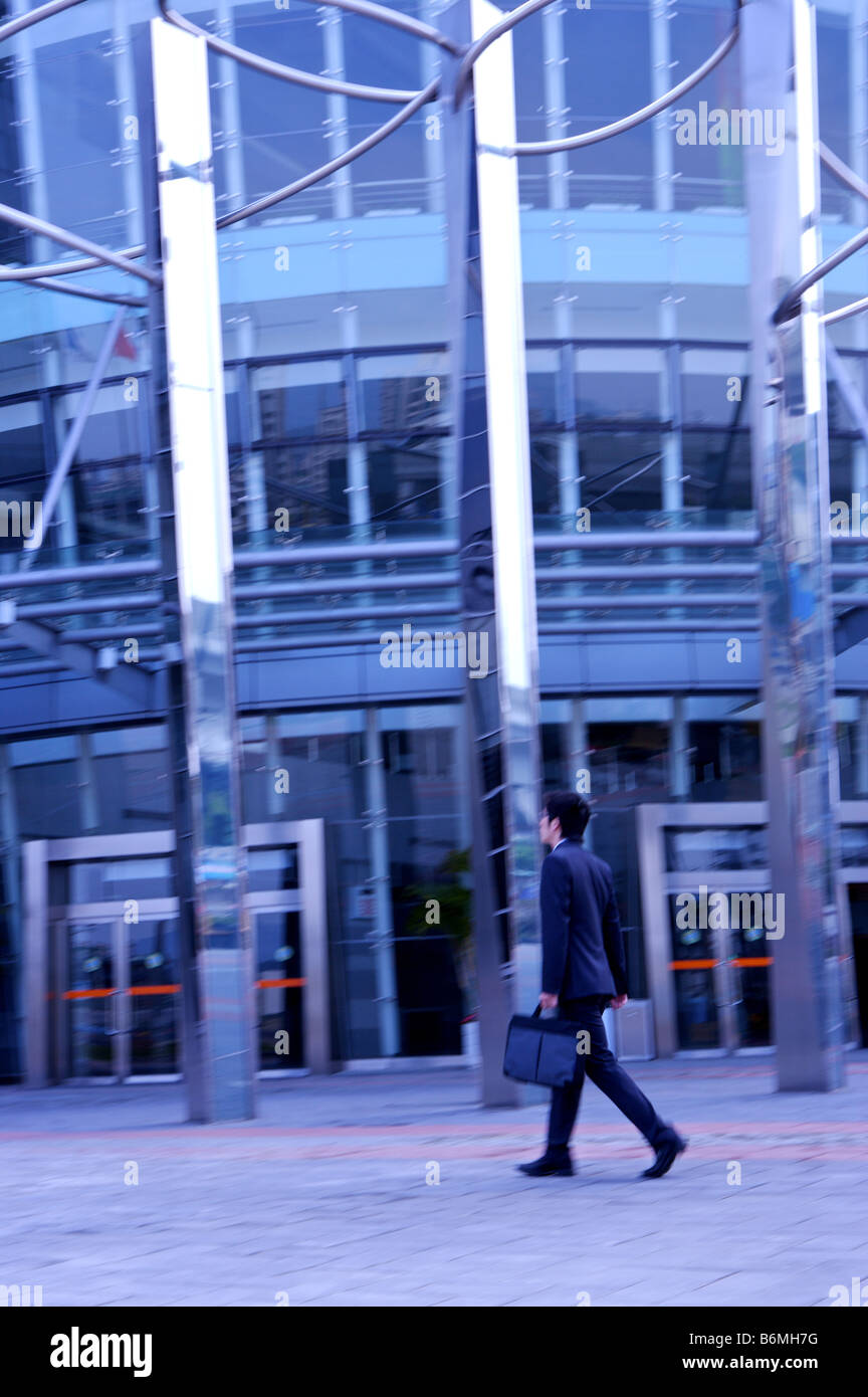 Businessman walking in front of office building Stock Photo - Alamy