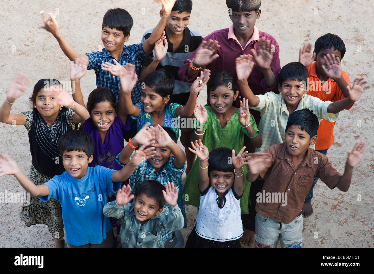 Indian children playing together huddled in a group waving at the ...