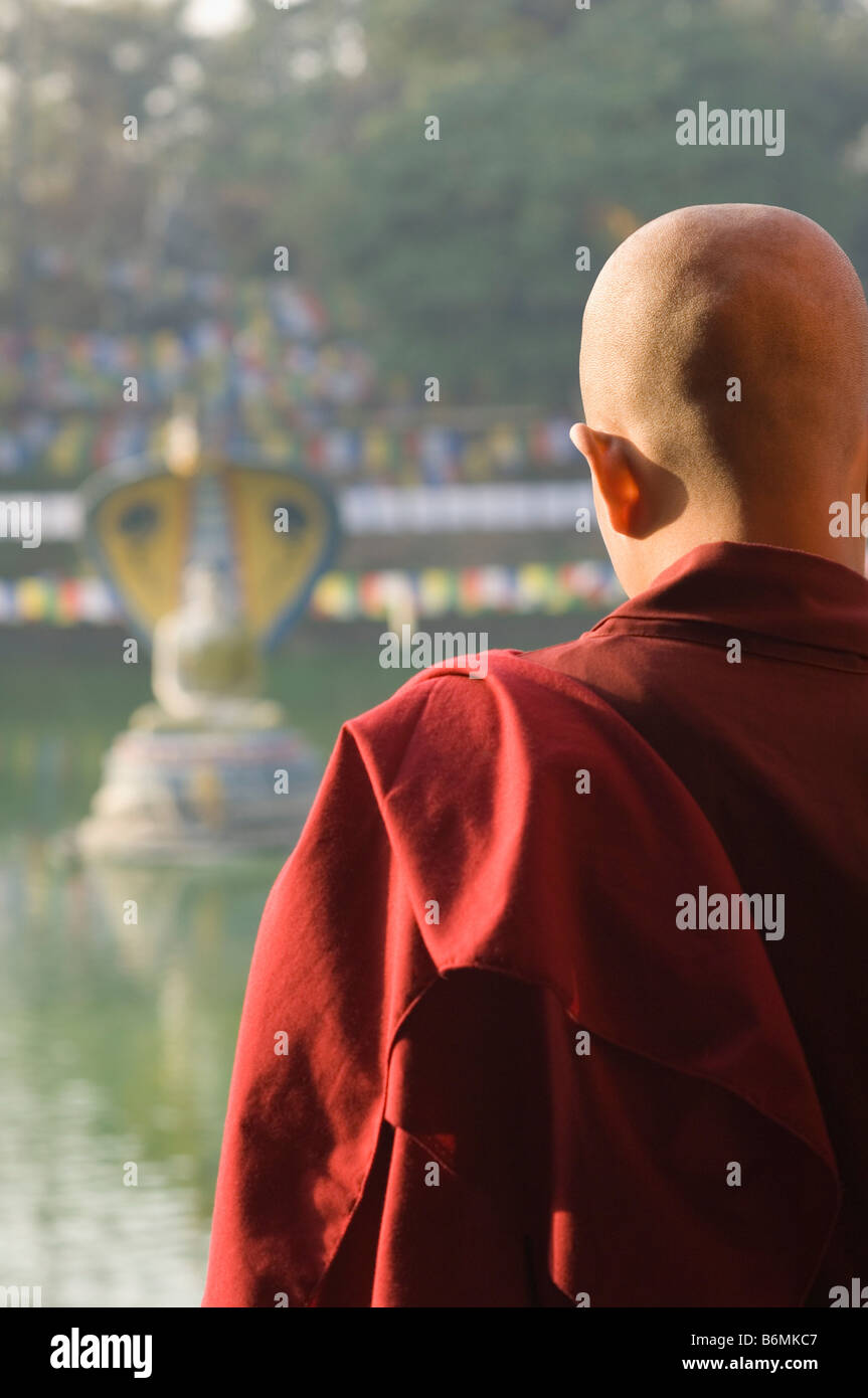 Rear view of a monk standing at the lakeside, Mucalinda Lake, Bodhgaya ...