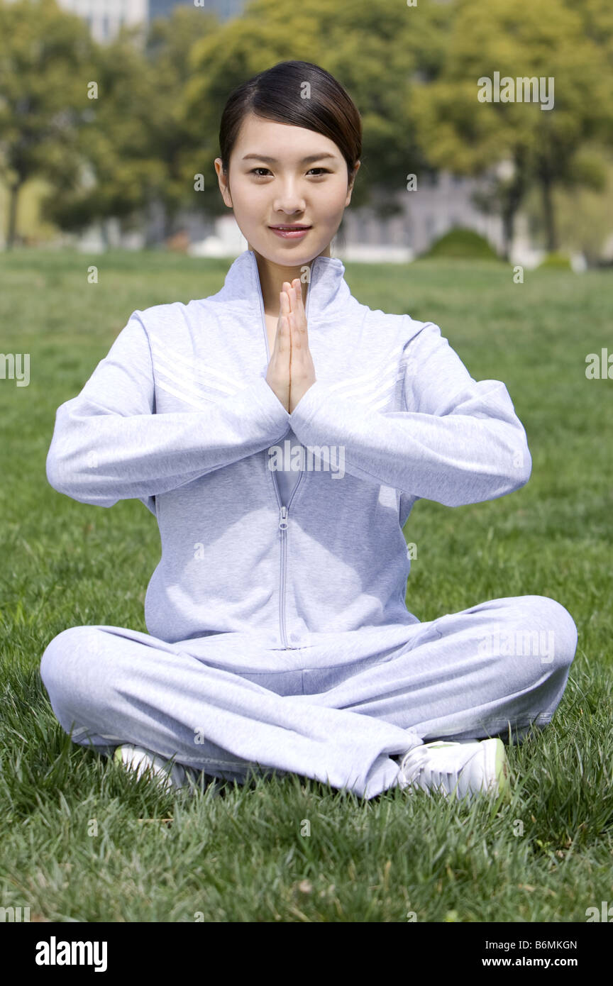 Young woman sitting on lawn in prayer position Stock Photo - Alamy
