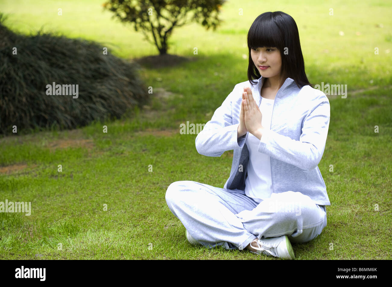 Young woman sitting on lawn in prayer position Stock Photo - Alamy