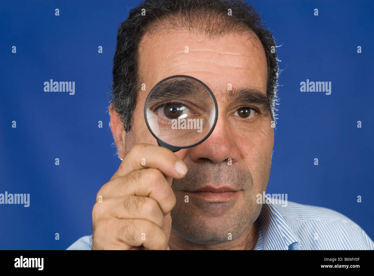 Man looking through magnifying glass Stock Photo - Alamy