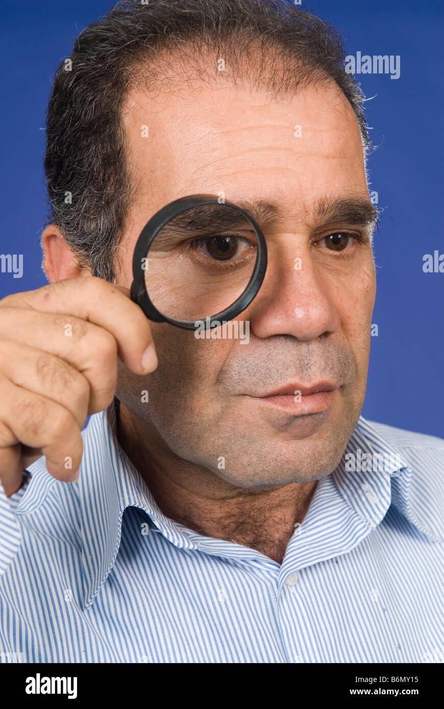 Man holding a magnifying glass in front of his eye Stock Photo - Alamy