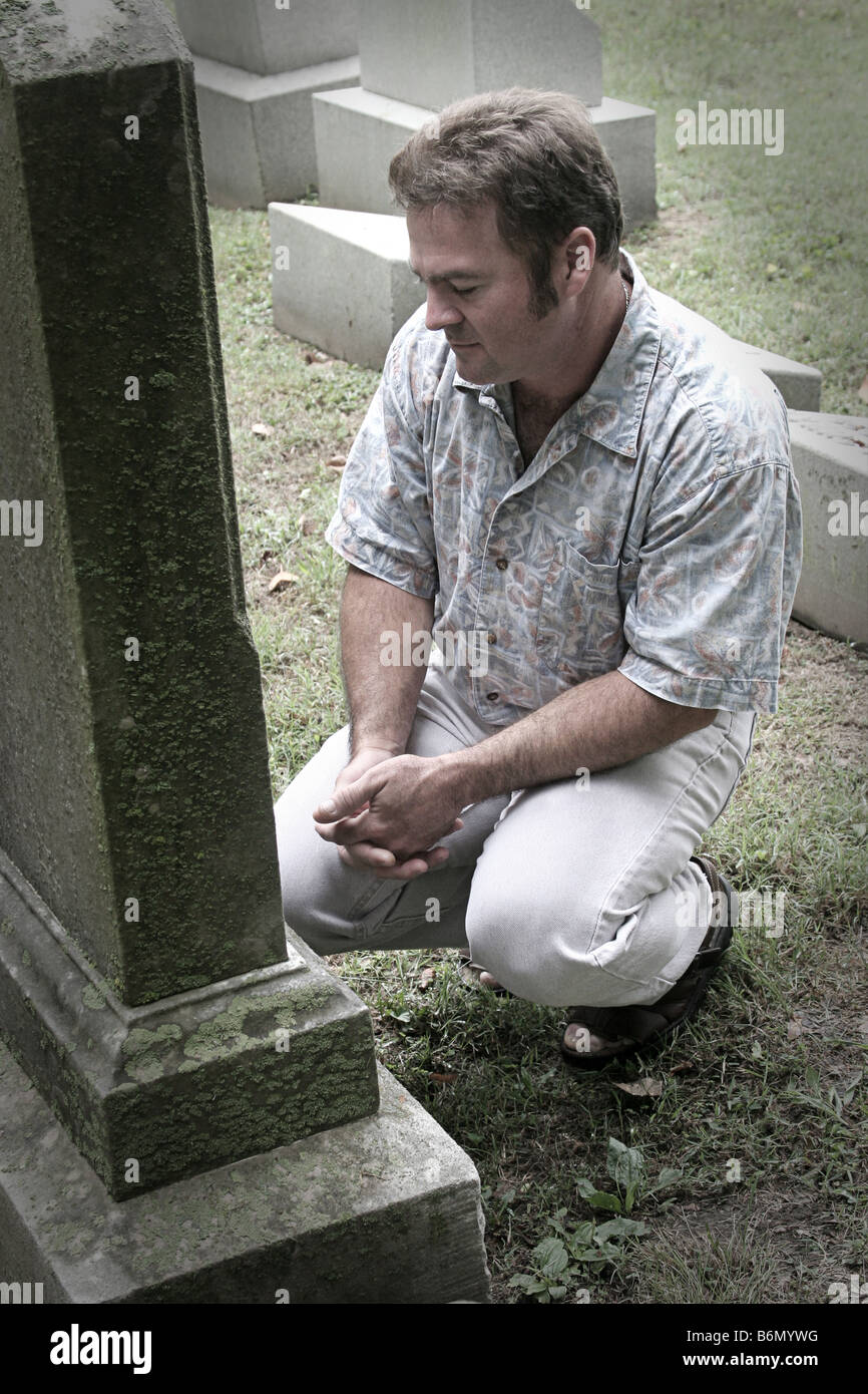 a man in a graveyard with hands folded in reverence partly desaturated ...