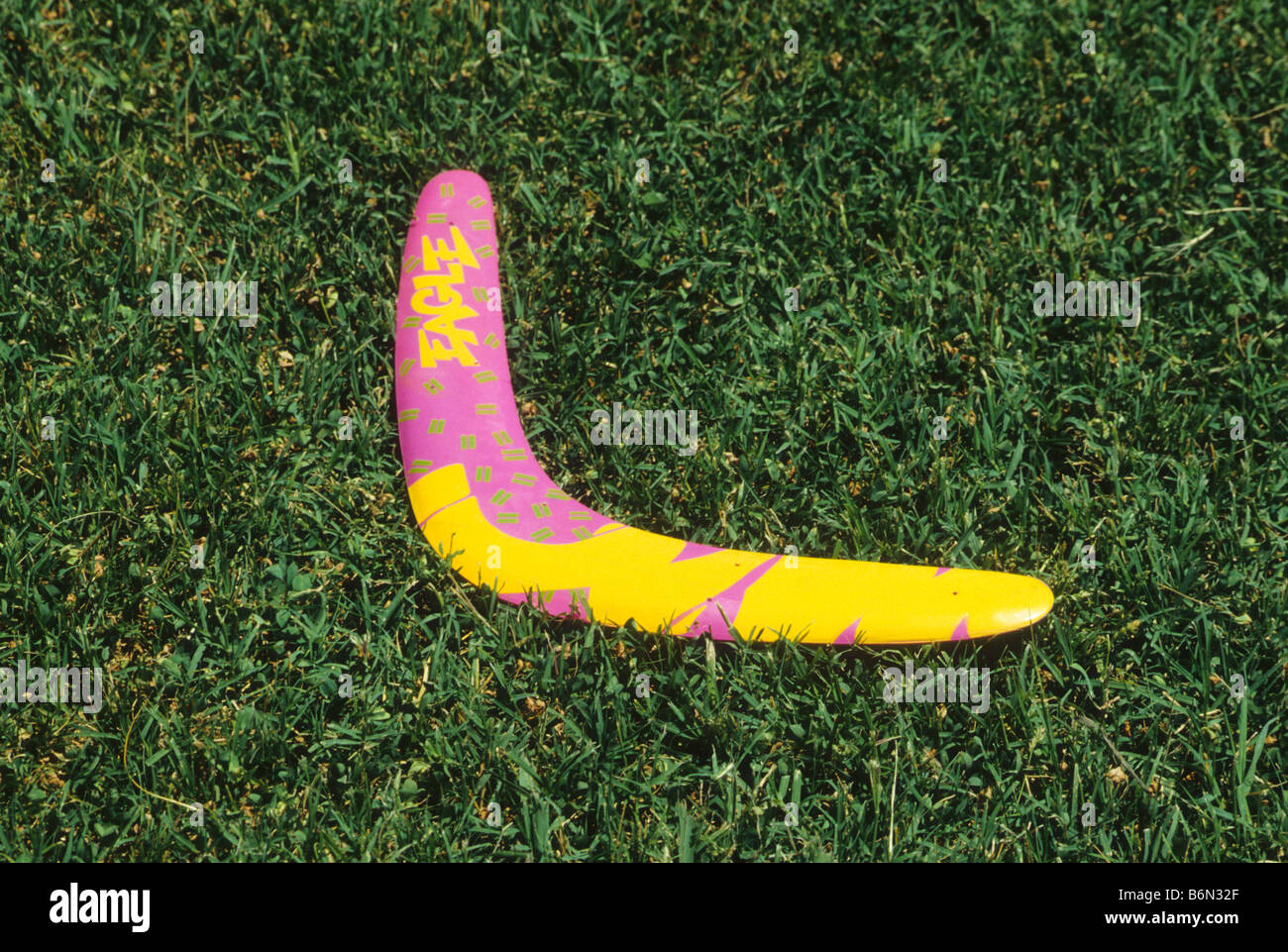Pink and yellow boomerang rests on grass Stock Photo - Alamy