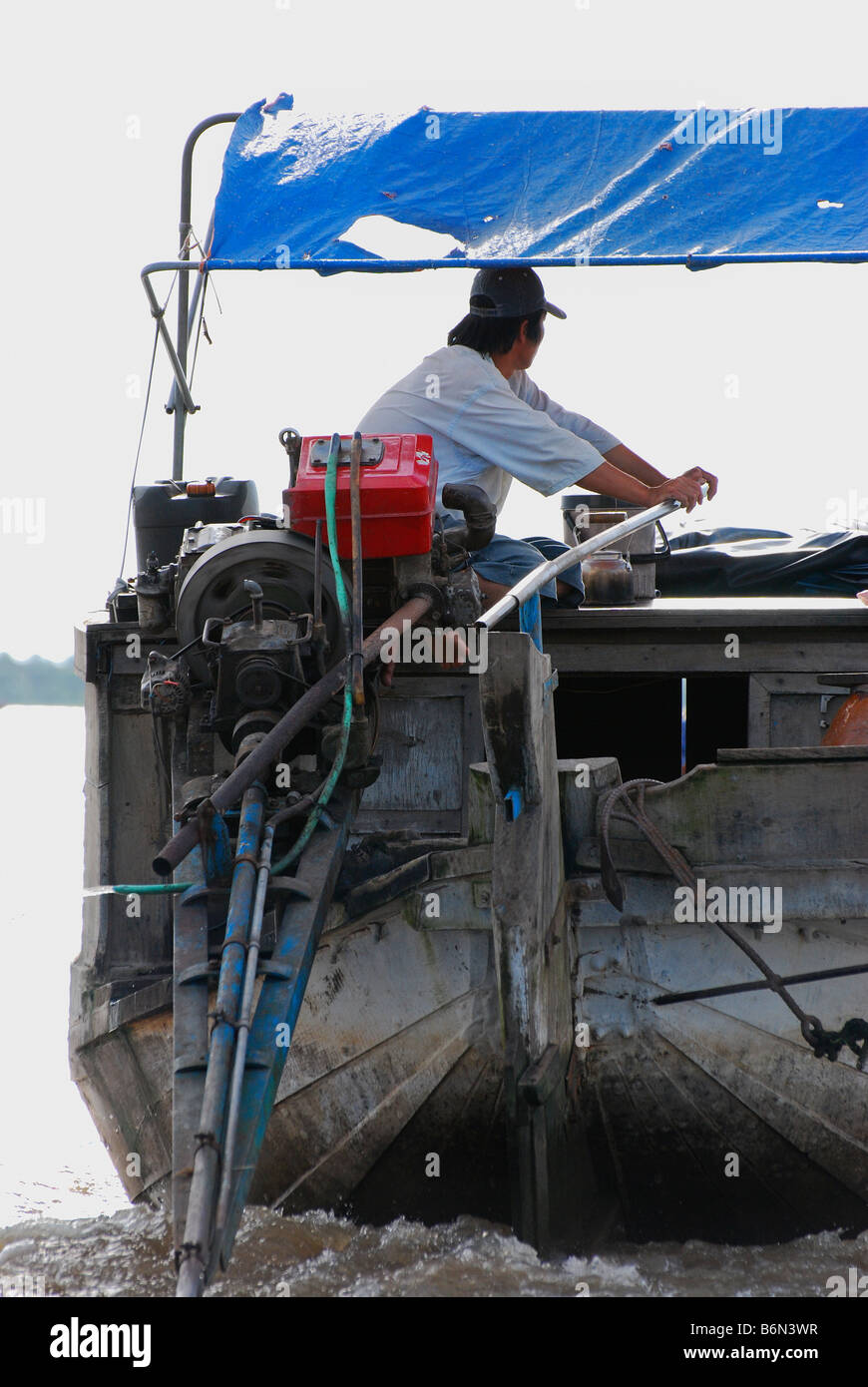 Skipper steering river boat with engine on pole, Co Chien River, Mekong ...
