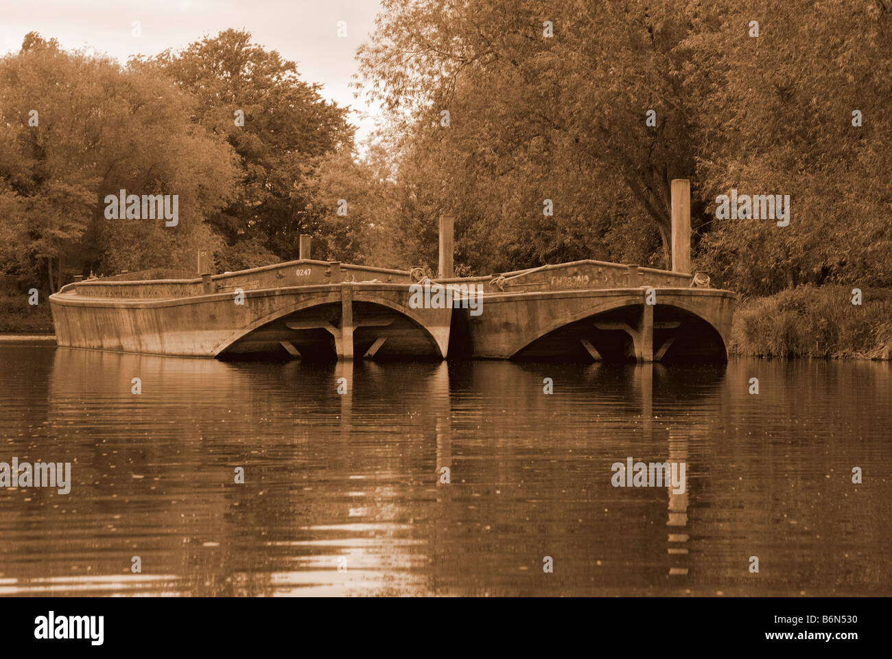Sepia toned: Two large, open topped working barges moored on a bend of ...