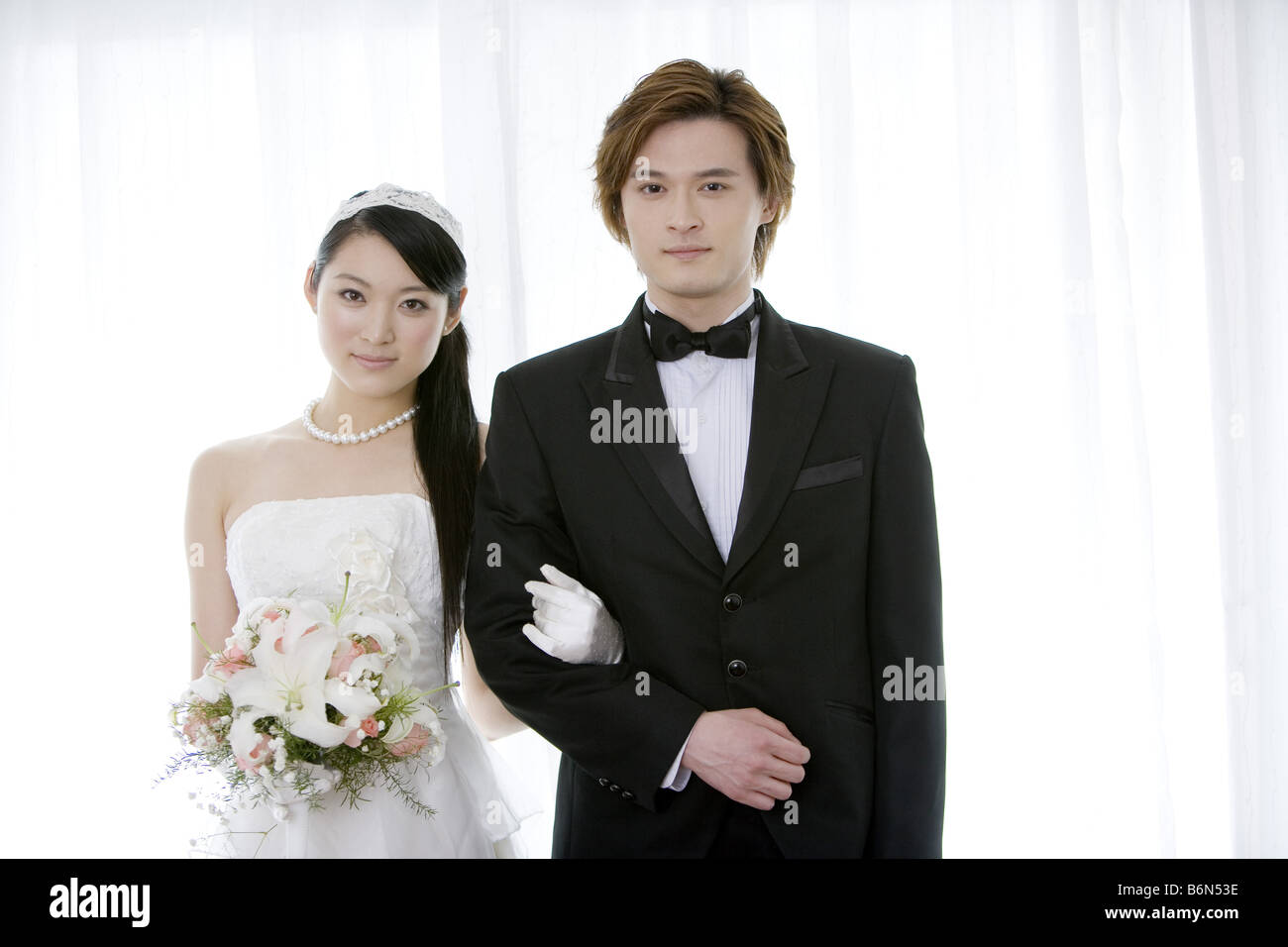 Bride and groom standing arm in arm portrait front view Stock Photo - Alamy