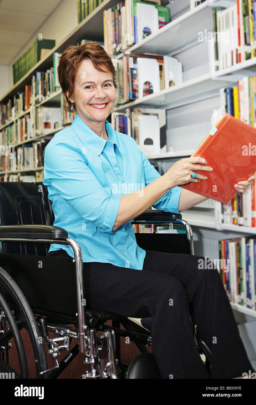 A pretty librarian in her wheelchair shelving books Stock Photo - Alamy