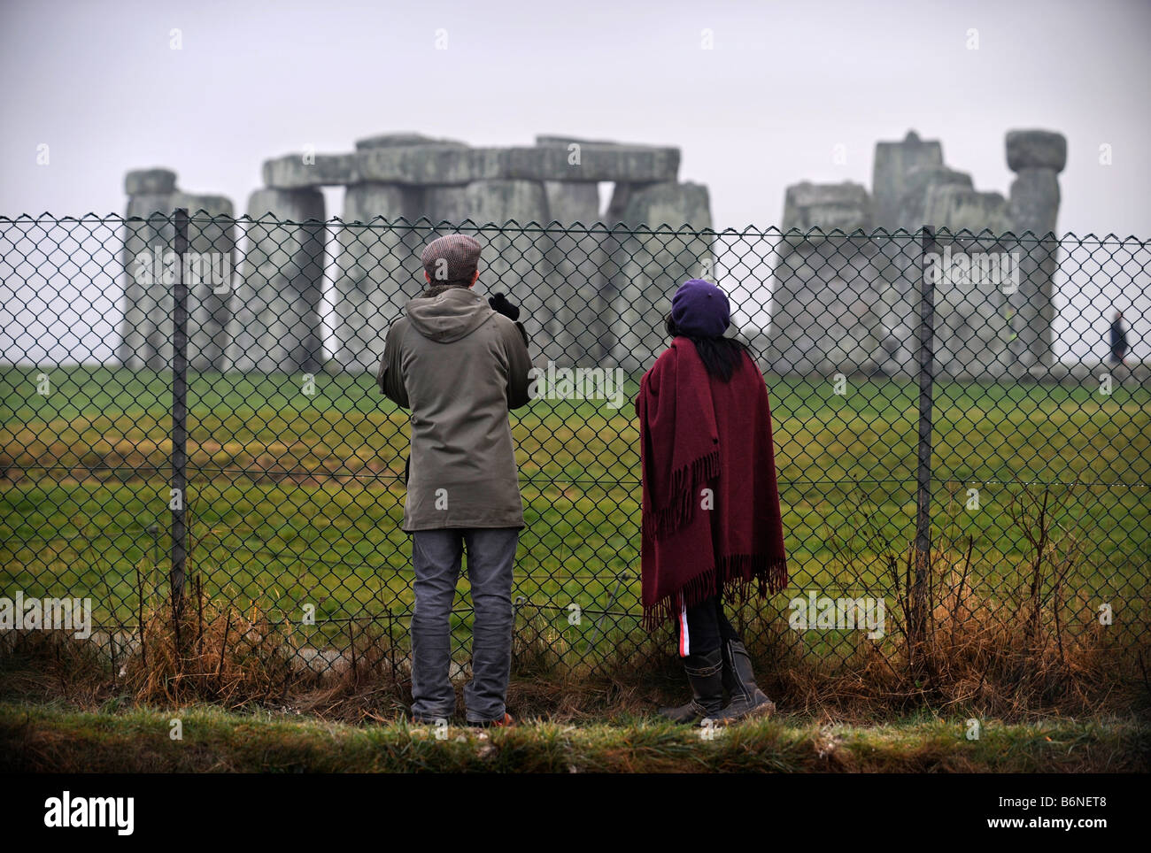 A COUPLE VISITING STONEHENGE PEER THROUGH THE FENCE AFTER THE ...