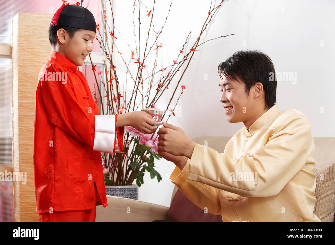 boy in traditional costume offering tea for his father Stock Photo - Alamy