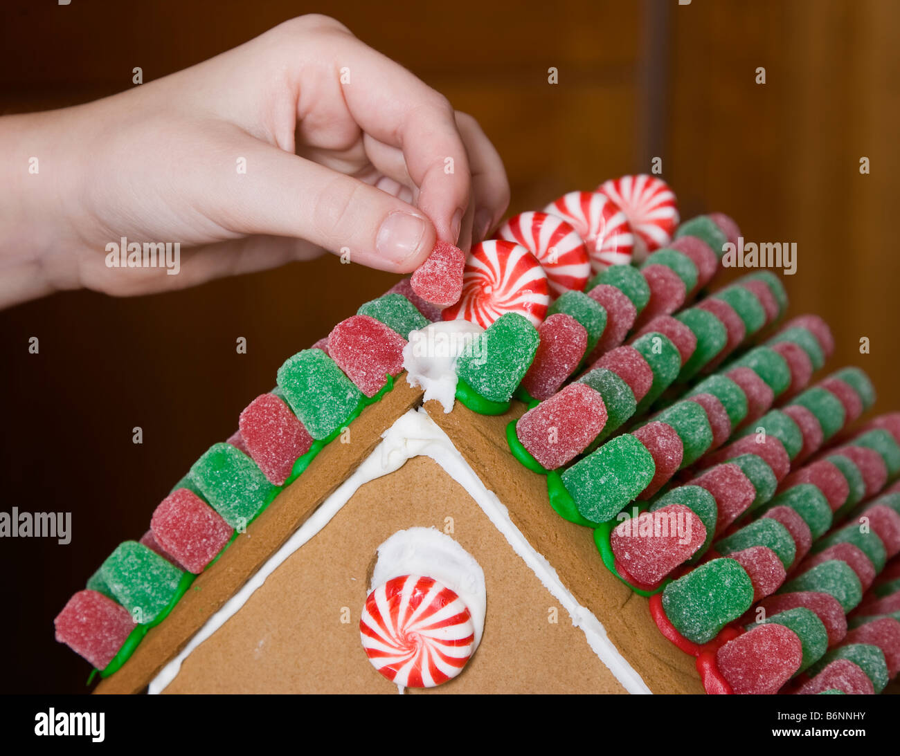 Child placing a gumdrop on the roof of a gingerbread house Stock Photo ...