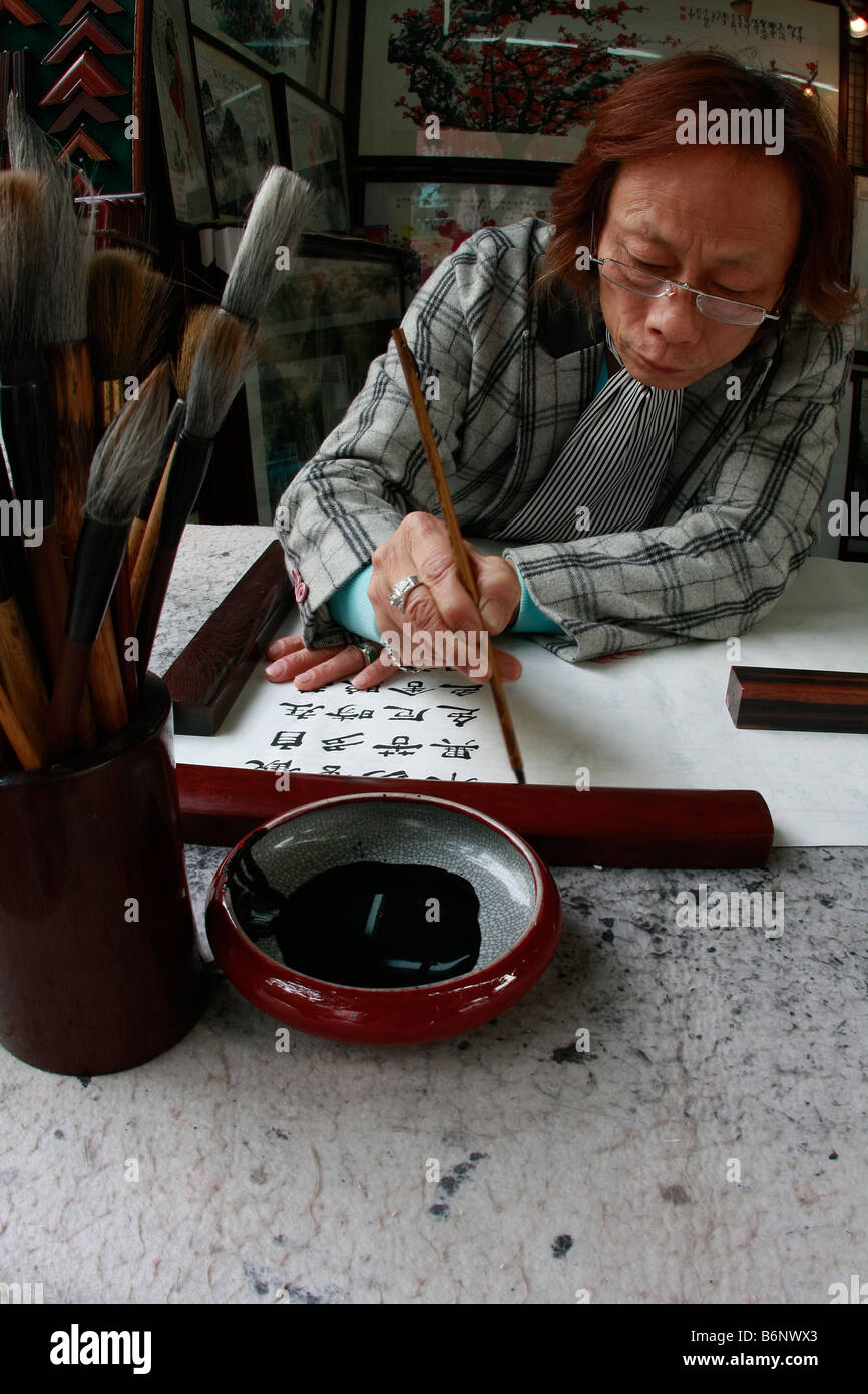 Chinese artiest and shop owner sitting creating a new artwork piece ...