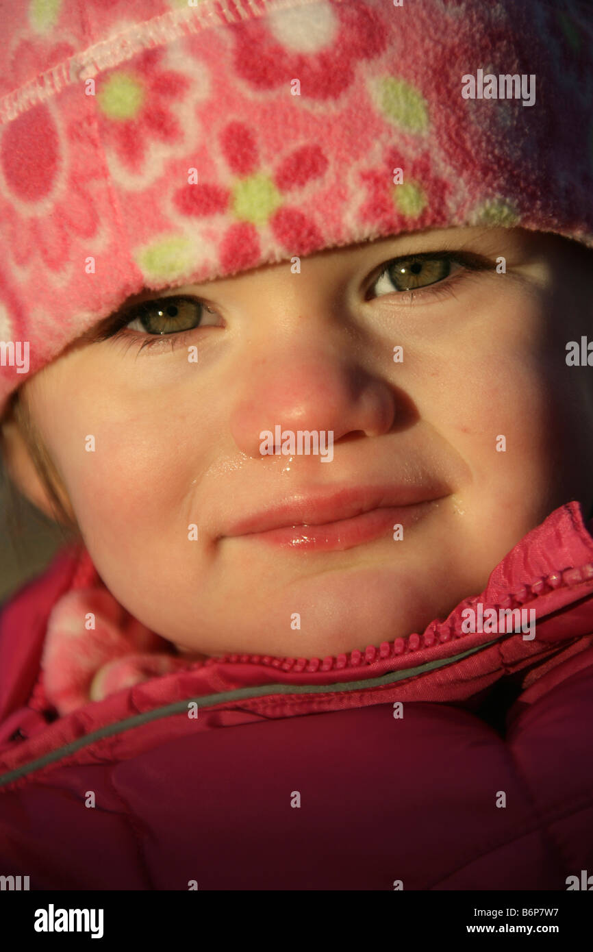 Close up portrait of a toddler looking thoughtful and cold with a runny ...