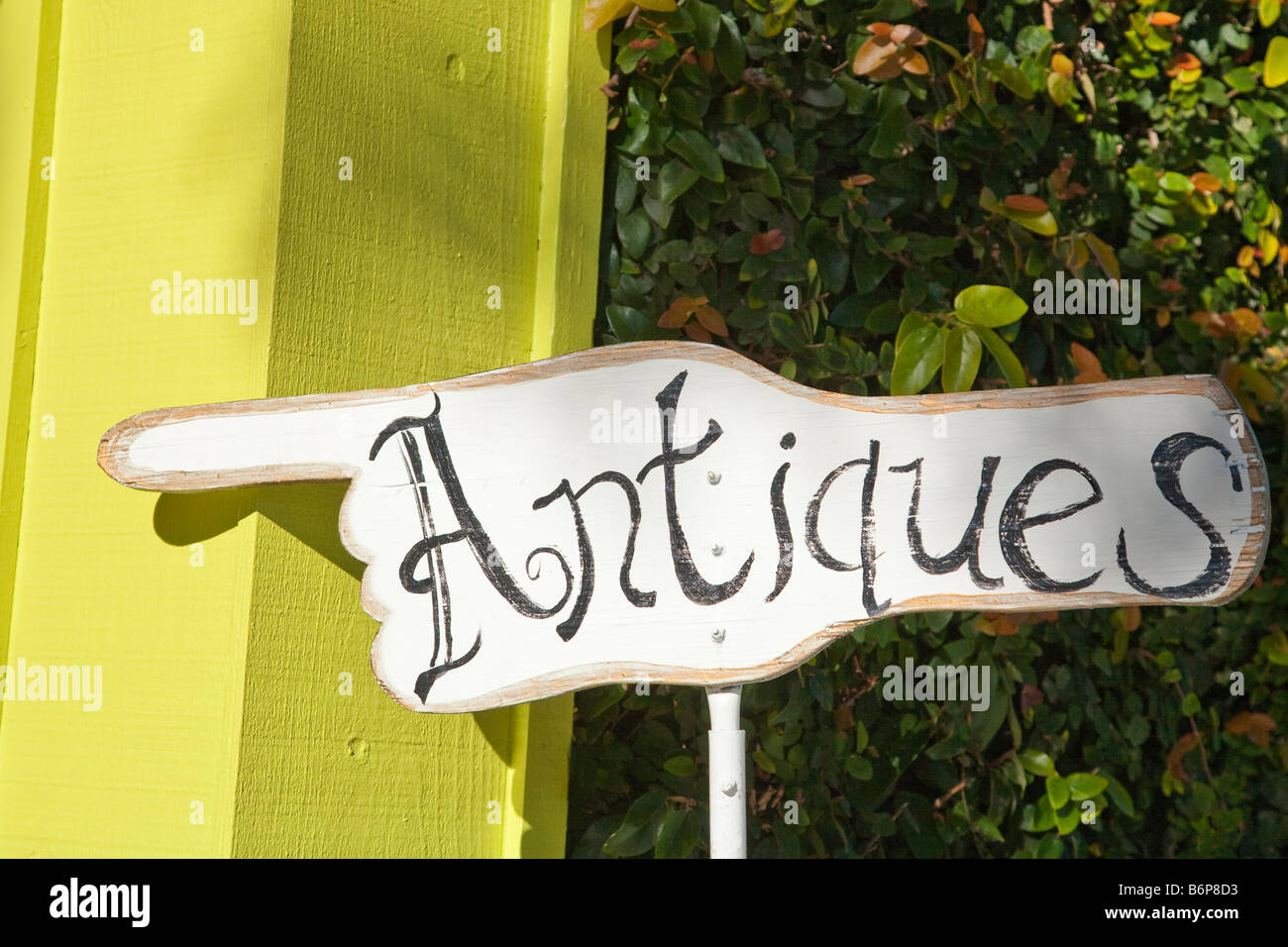 An old fashioned hand pointing sign has the word antiques written in ...