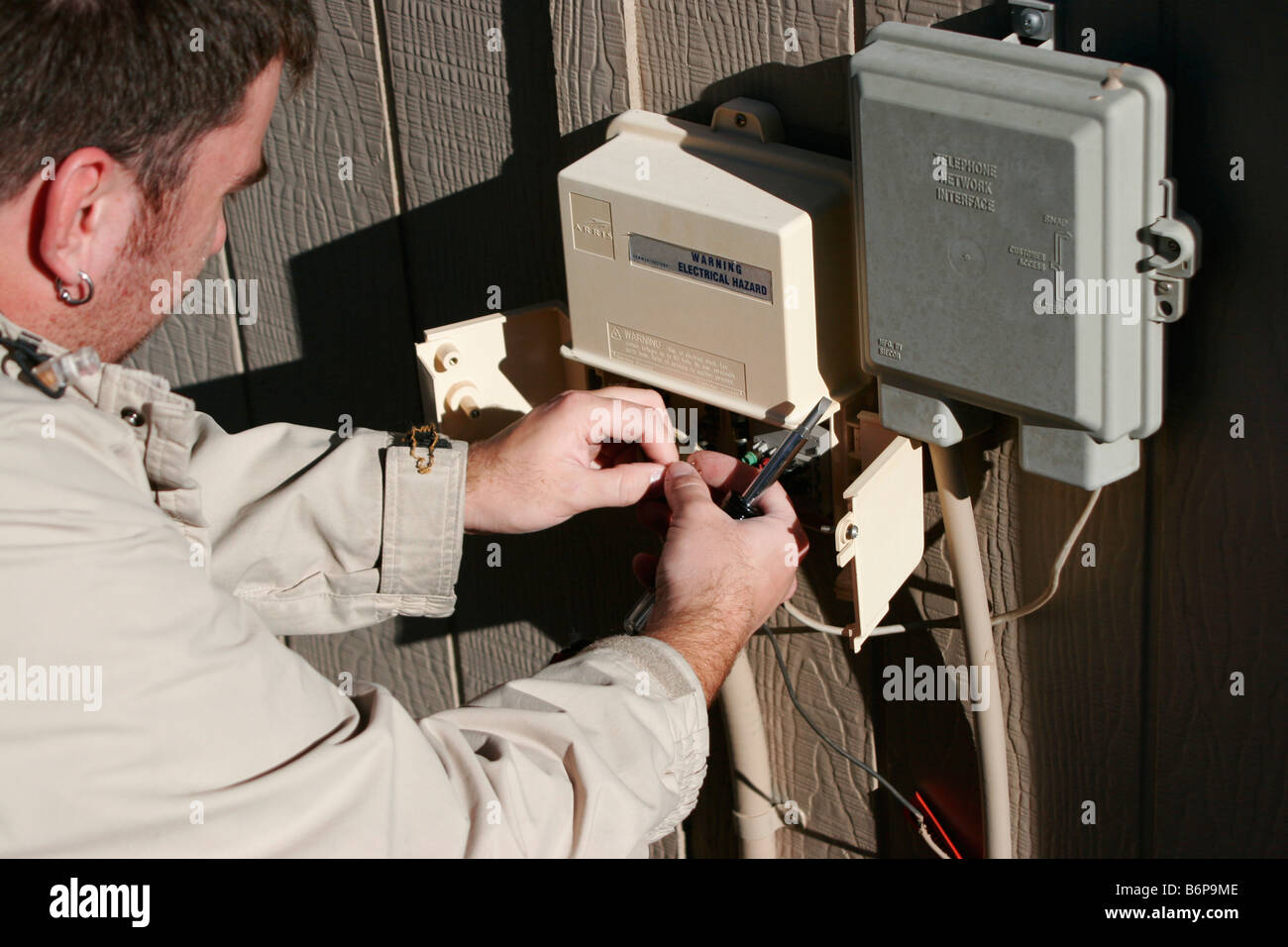 A telephone repairman makes an adjustment on a wiring connection while ...