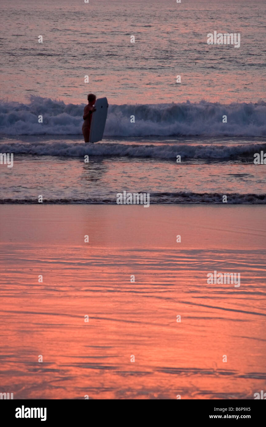 Surfer takes to waves during colorful sunset at Flamingo Beach in Costa ...