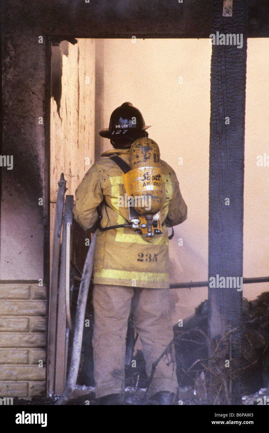 Fireman enters buring home with firehose to fight fire Stock Photo - Alamy