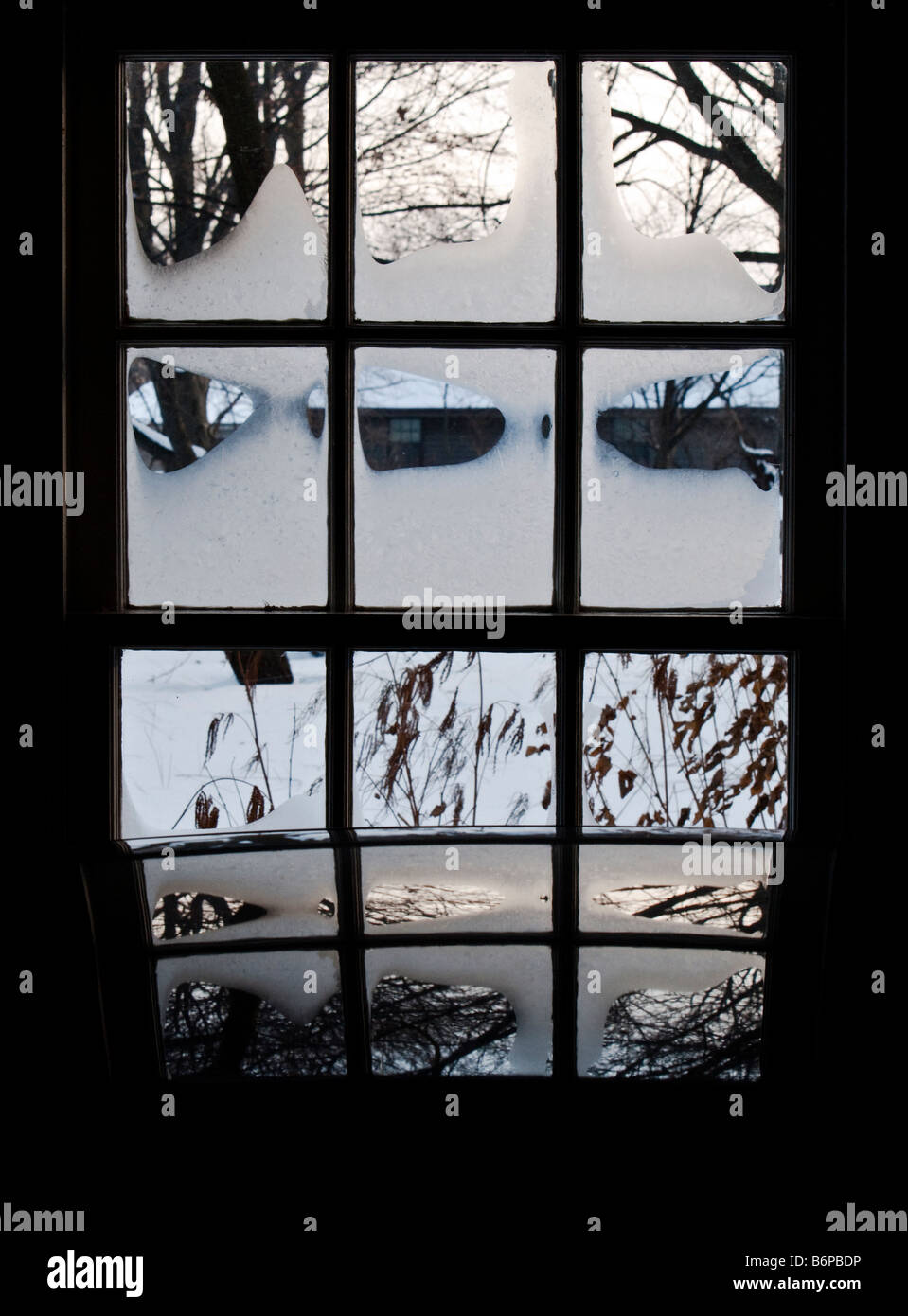 A frost-covered window in a suburban garage is reflected in the roof of ...