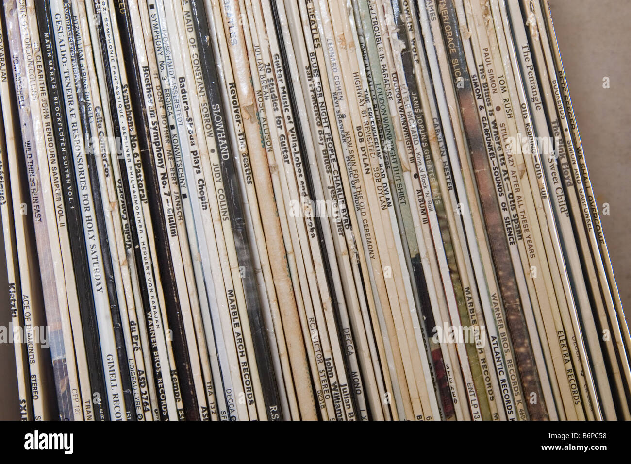 A stack of worn vinyl records (LPs) viewed from the spines with titles ...