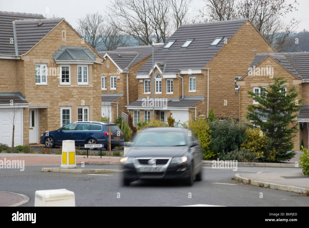 houses on a new estate with a car going round a roundabout in the ...