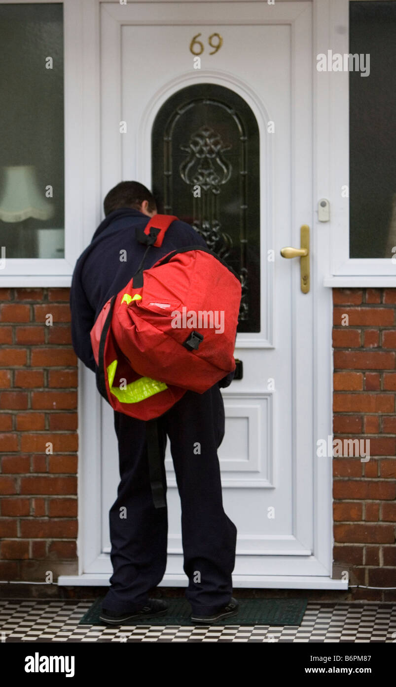 A Royal Mail postman delivers letters through a door on his round in ...