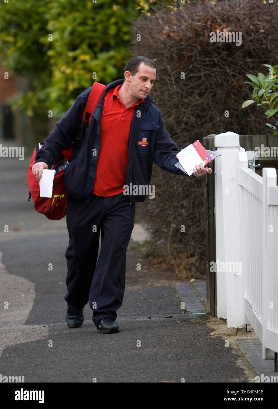 A Royal Mail postman walks on his round delivering letters in Essex U K ...
