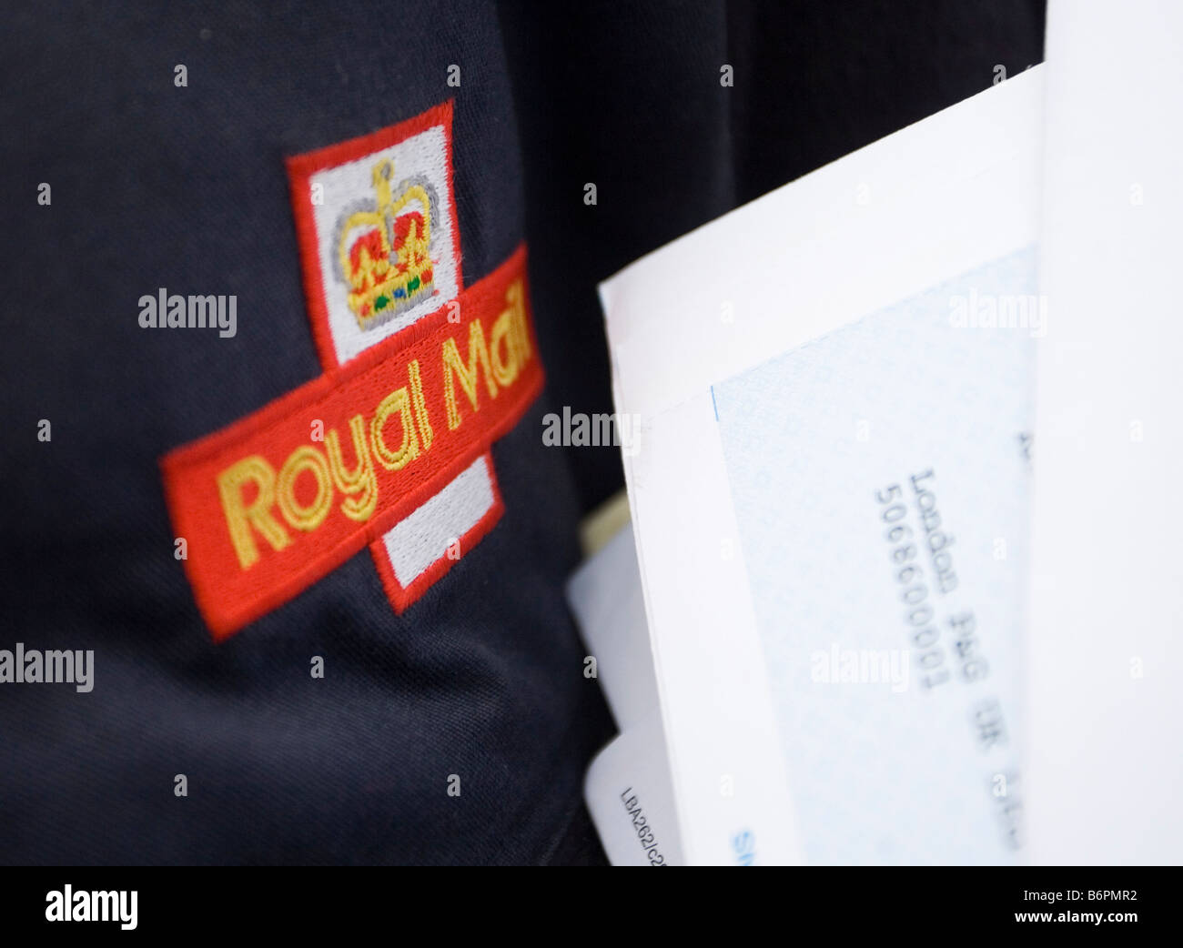 A Royal Mail postman holds letters close to his jacket badge in Essex U ...