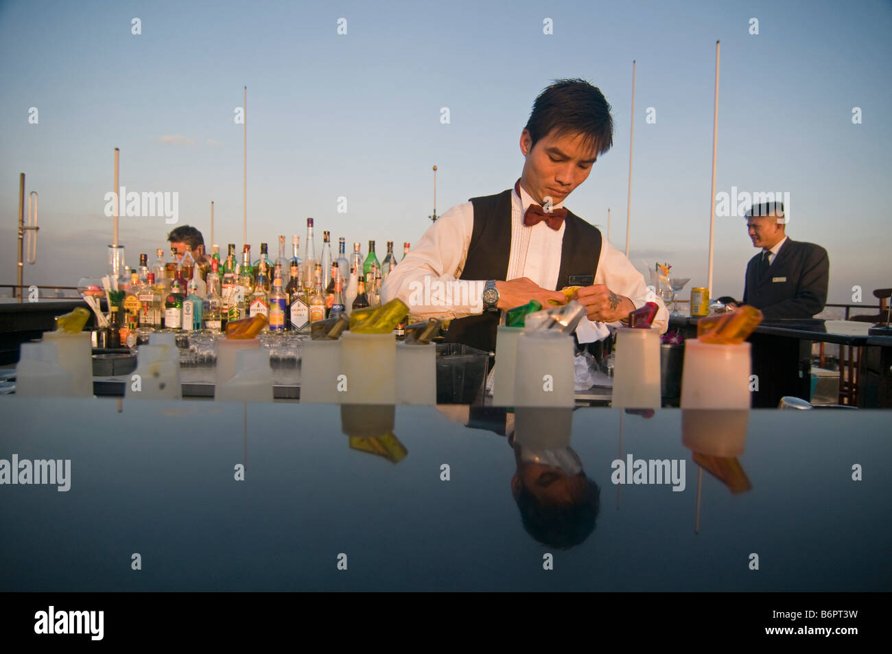 bartender mixing drinks at sunset on a rooftop bar in Bangkok Thailand ...