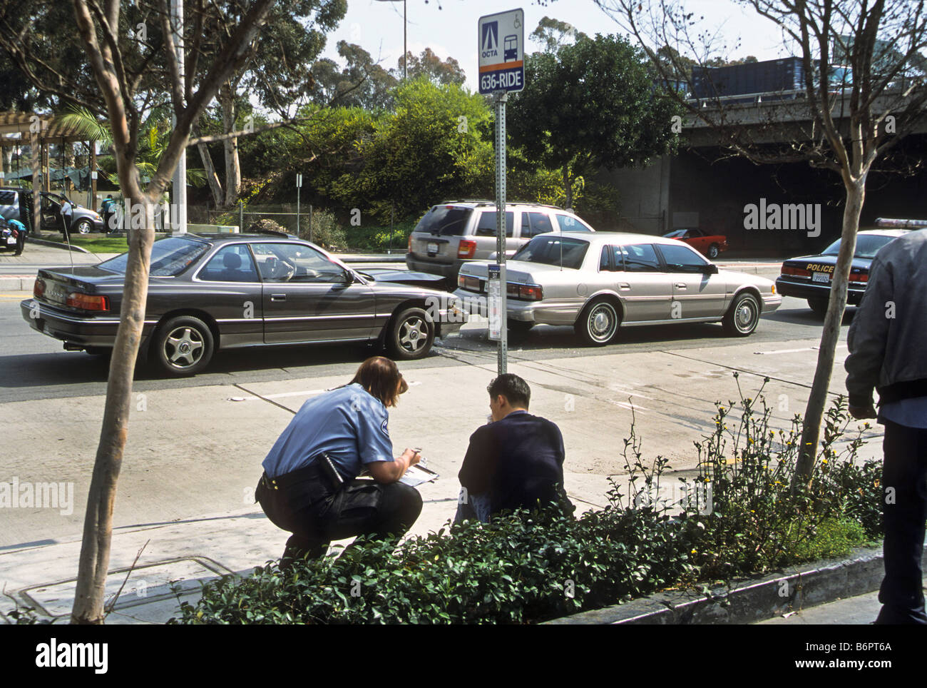 Police officer interviews victim of auto accident as they wait for tow ...