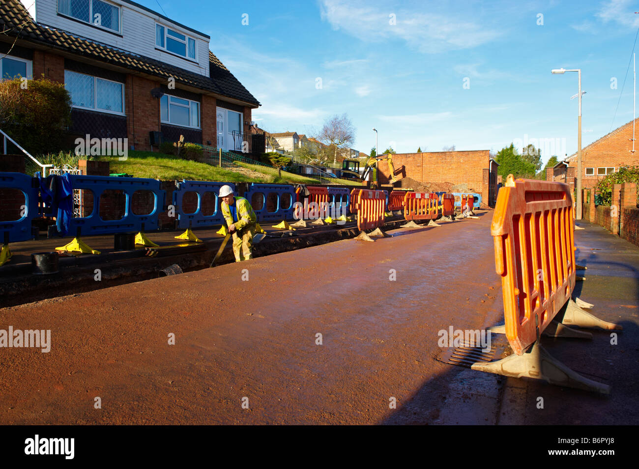 Workman laying electrical cabling in road Stock Photo - Alamy