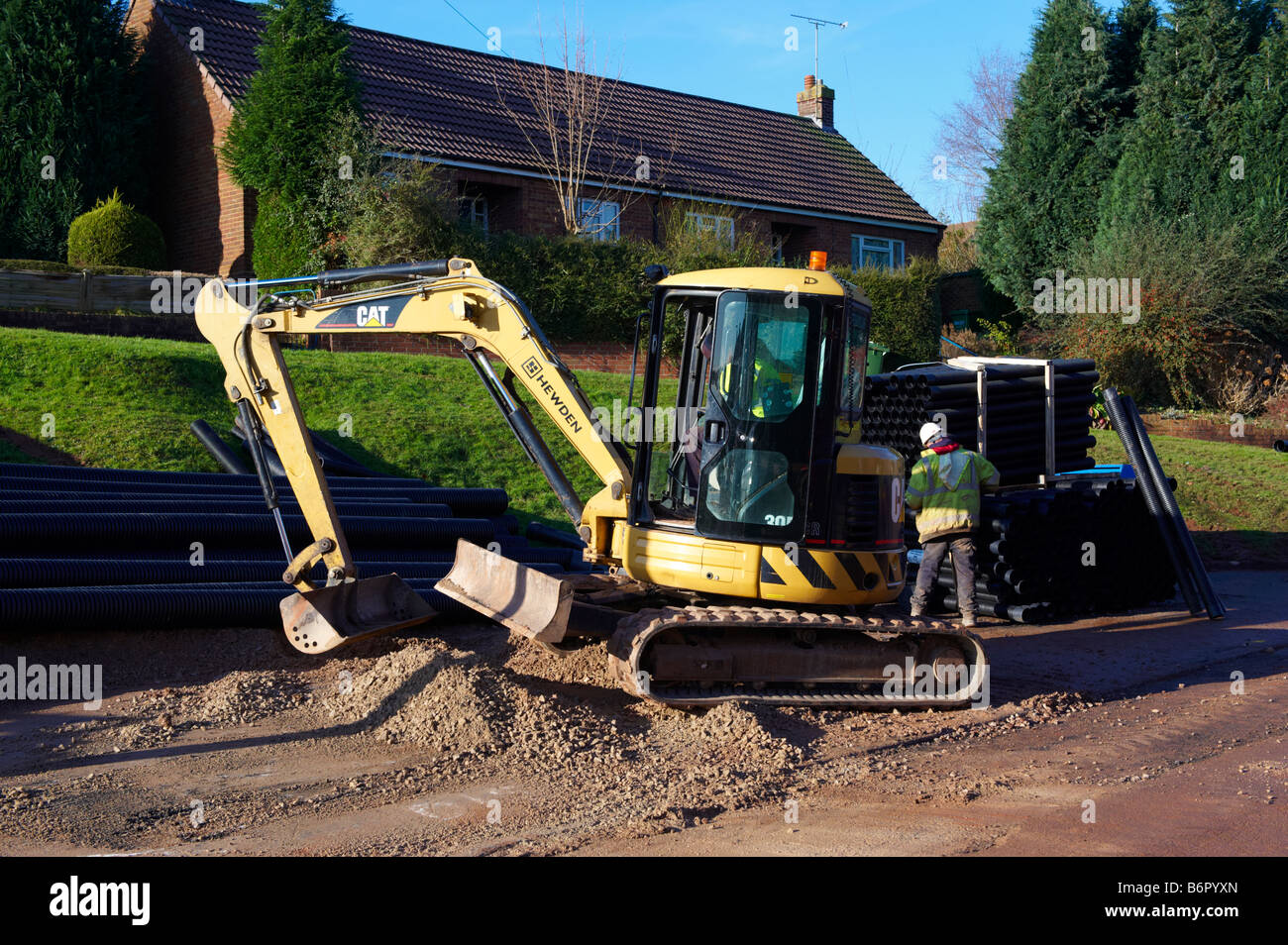 Road digger tractor working on road after laying electrical cabling ...