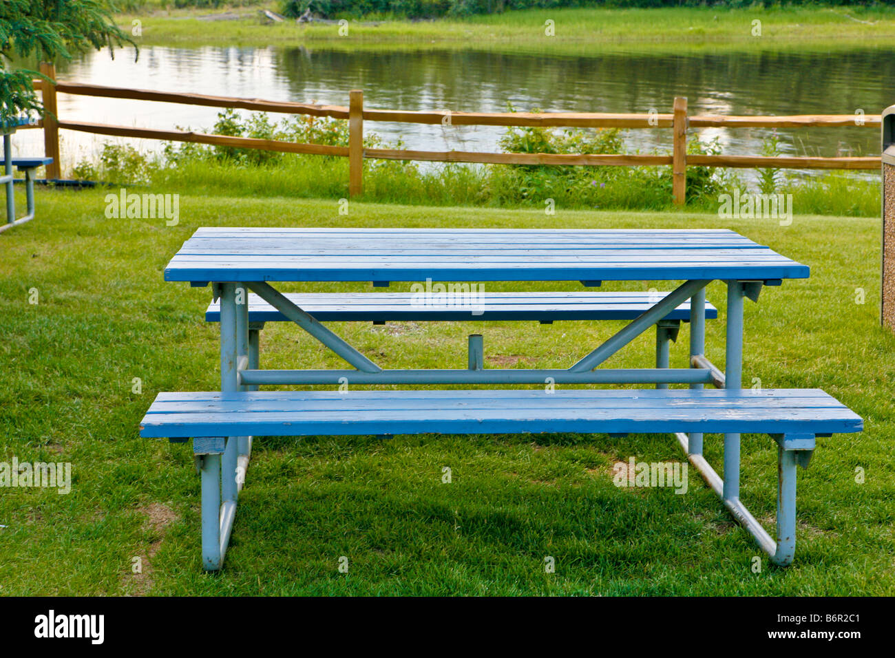 Blue picnic table on grass along river with wooden rail fence Stock ...