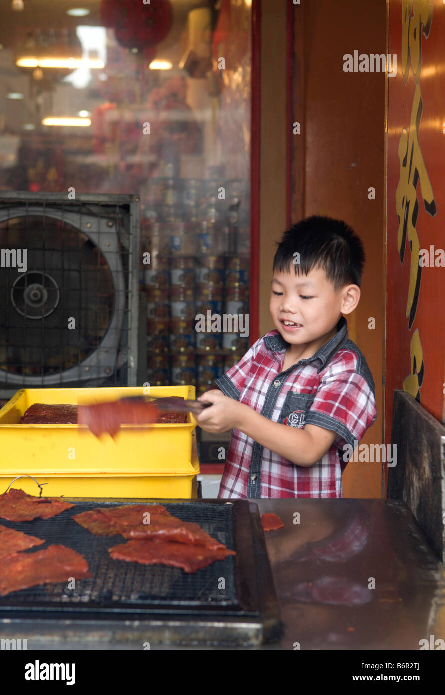 Young boy cooking bakkwa or rougan Stock Photo - Alamy
