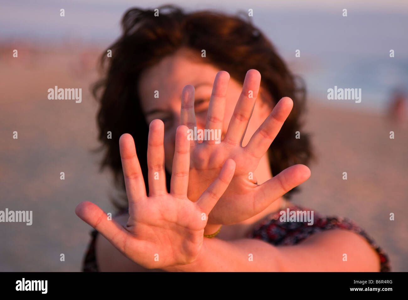 Woman trying to avoid picture in a beach during sunset Stock Photo - Alamy