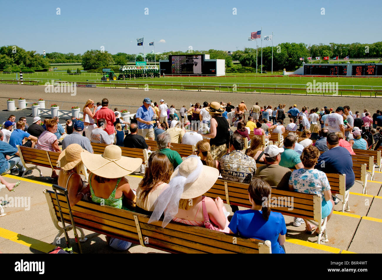 Female horse racing fans wearing hats watching the start of a turf race ...