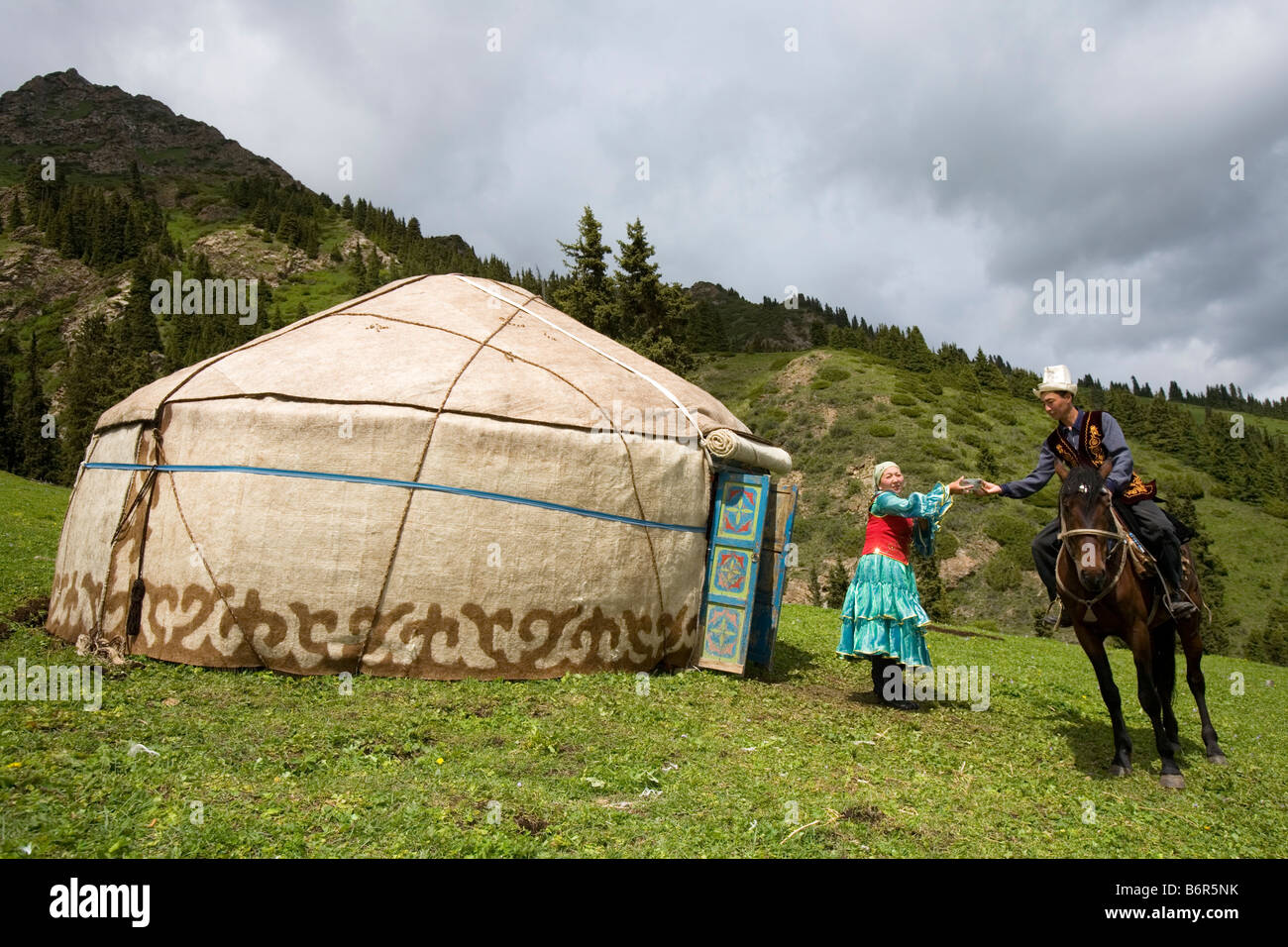 Kyrgyz man wearing traditional clothes receiving welcome tea from his ...