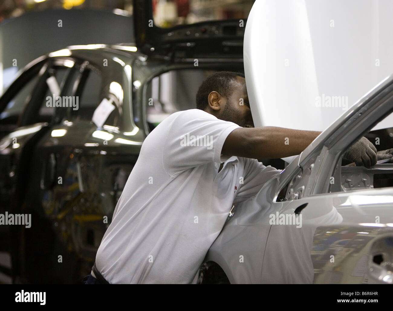 A worker at Toyota Final Assembly production line fits a part to a ...