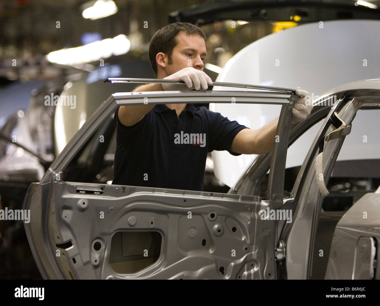 A worker at Toyota Final Assembly production line fits a part to a ...
