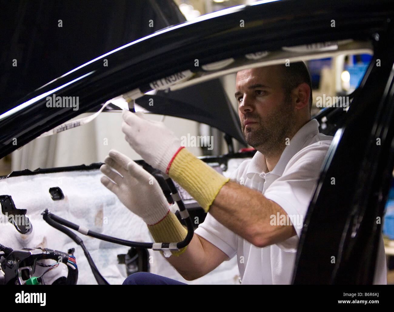 A worker at Toyota Final Assembly production line fits a part to a ...