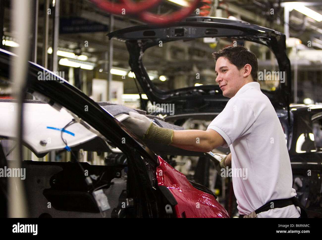 A worker at Toyota Final Assembly production line fits a part to a ...