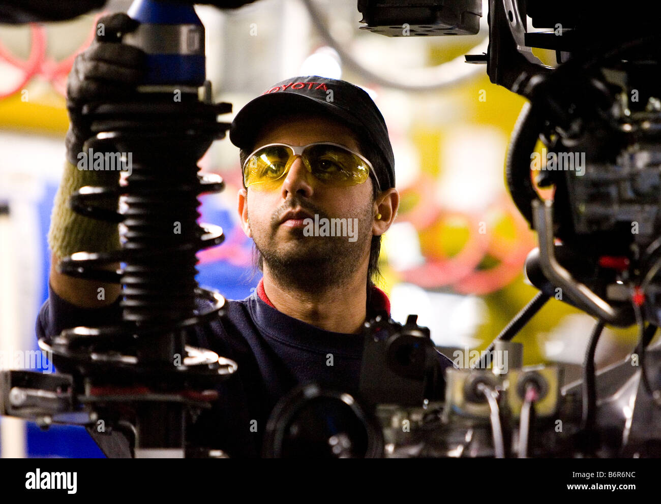 A worker at Toyota Final Assembly production line fits a part to a ...